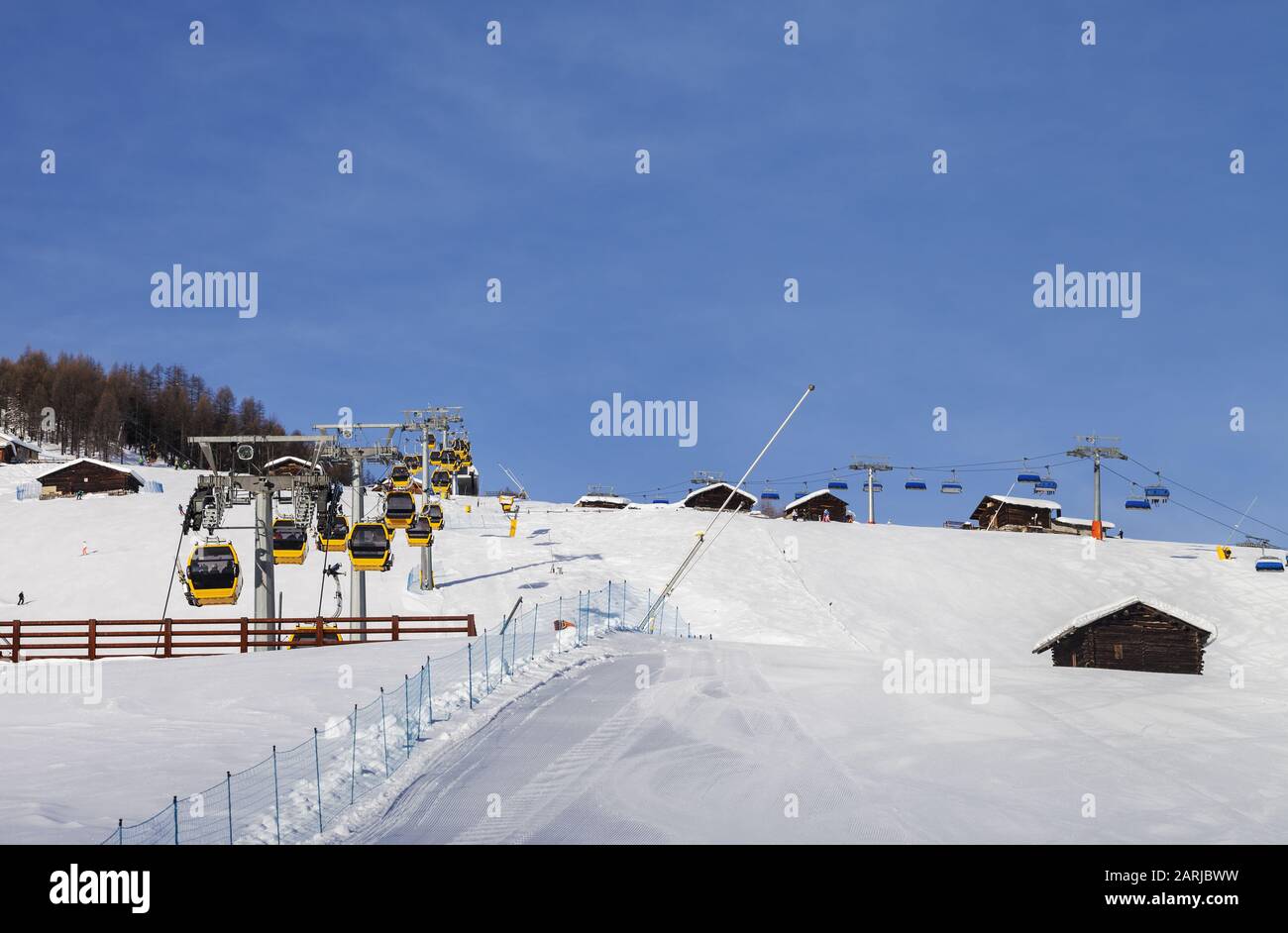 Snowy ski track prepared with snow grooming machine, gondola lift ...