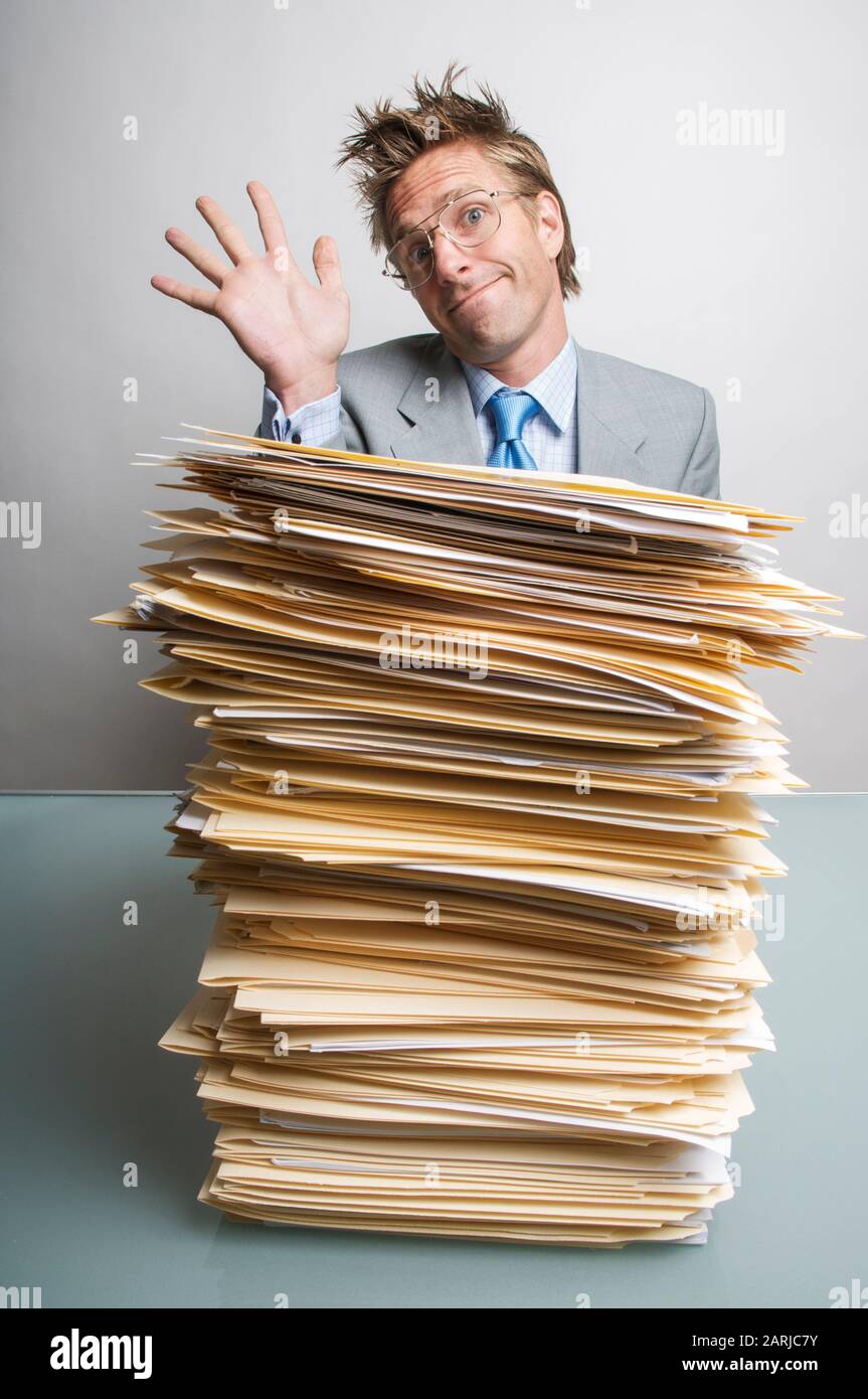 Cheerful office worker waving from behind a tall stack of file folders ...