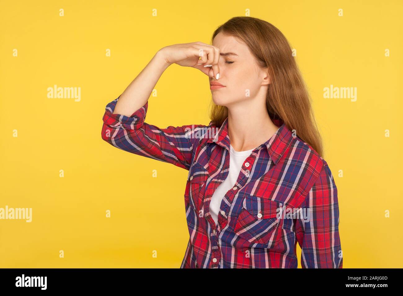 Disgusting smell! Portrait of displeased ginger girl in checkered shirt ...