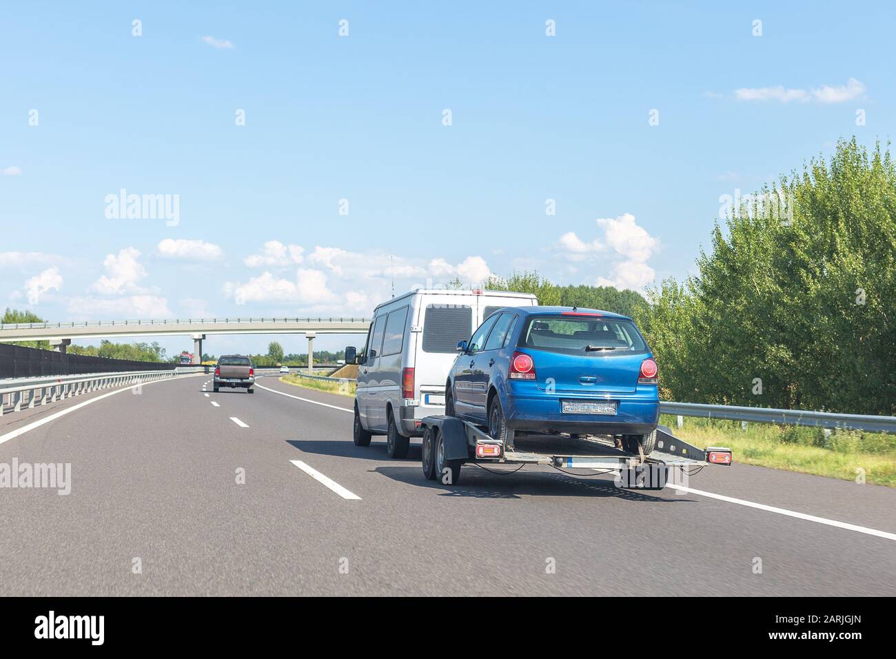 Car carrier trailer with blue car on highway Stock Photo - Alamy