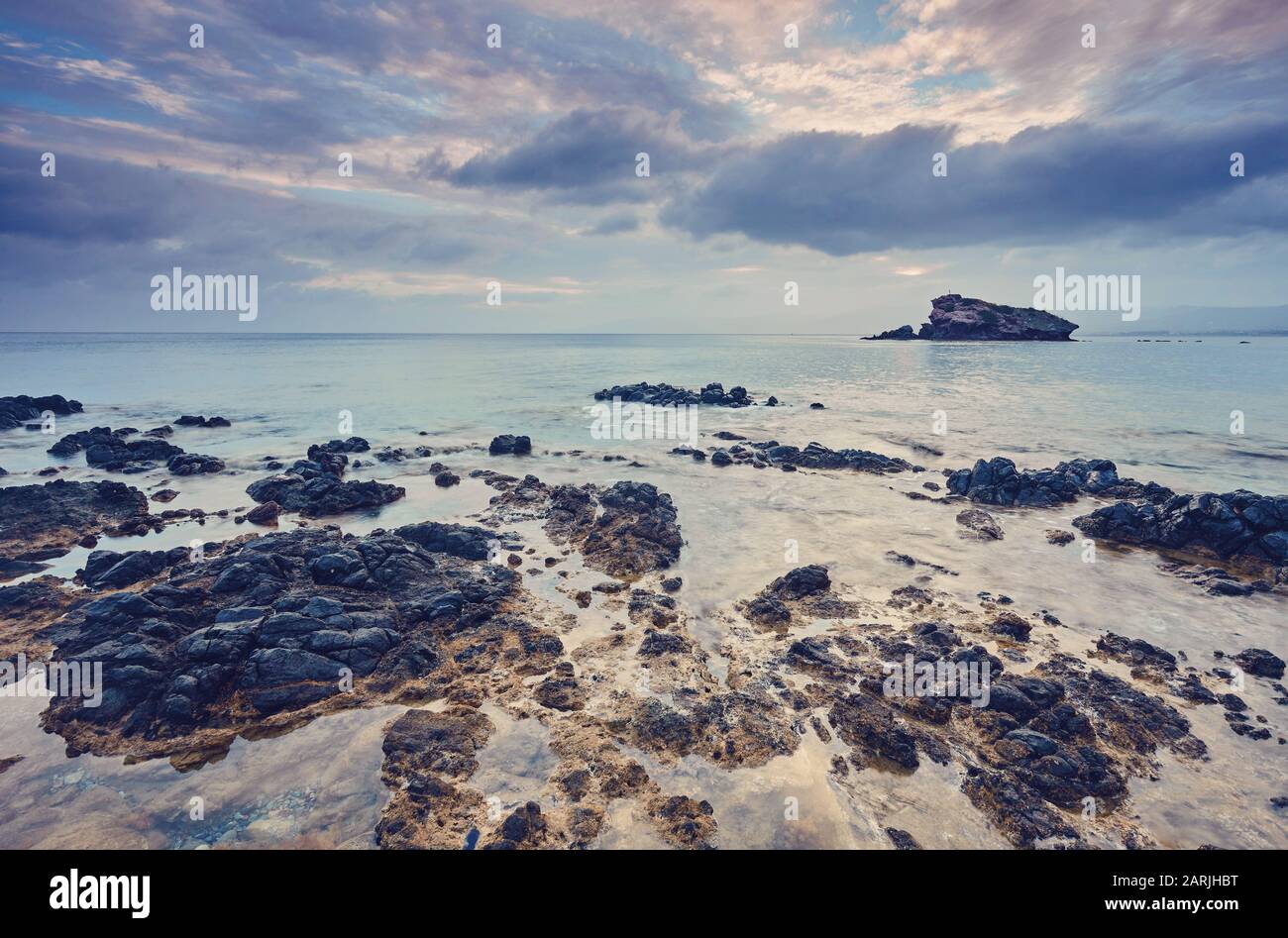 Stones and rocks in forefront with creamy surf ebbing and flowing on ...