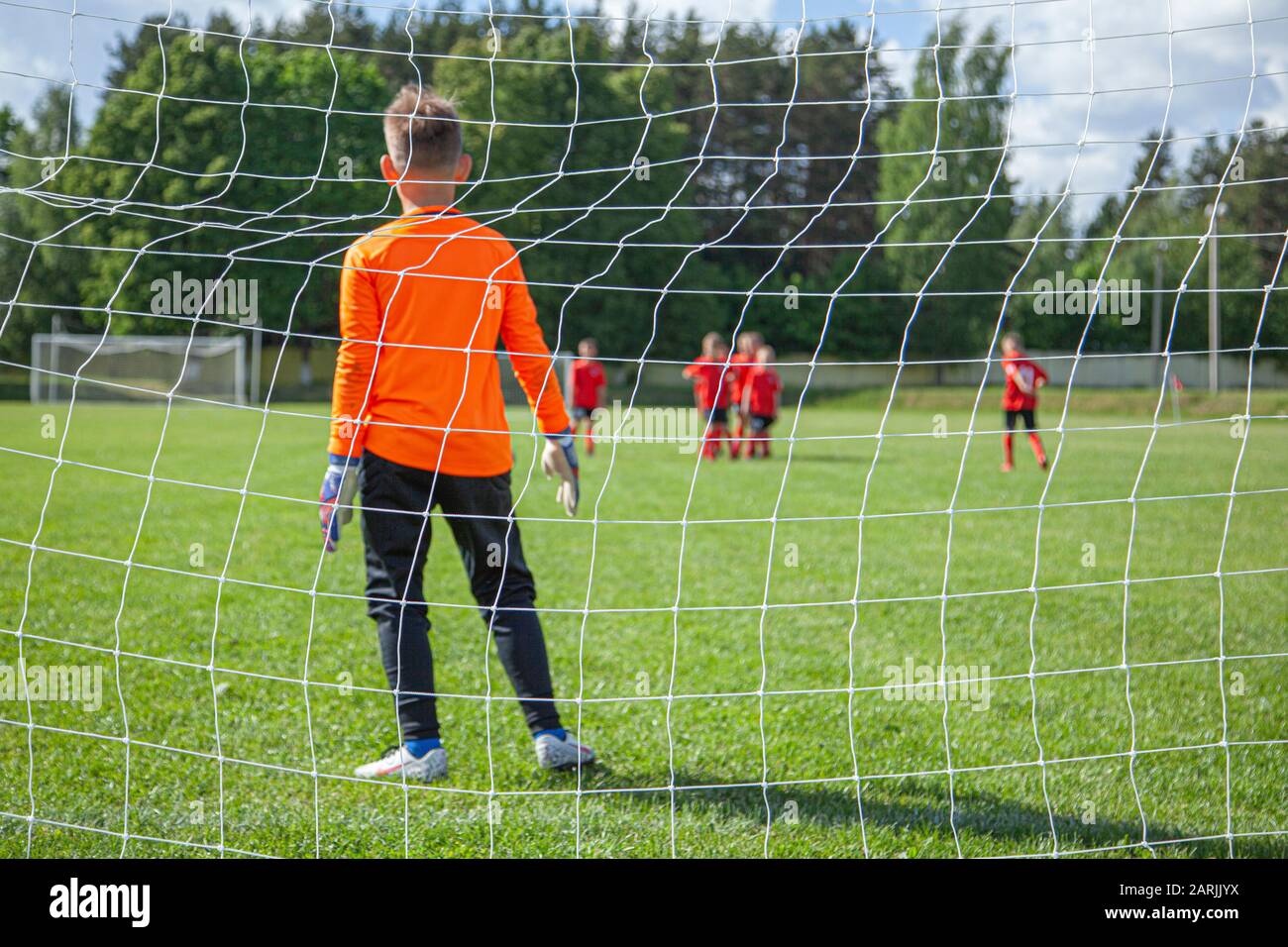 Goalkeeper catches the ball. Goal net in focus. Sports competition ...