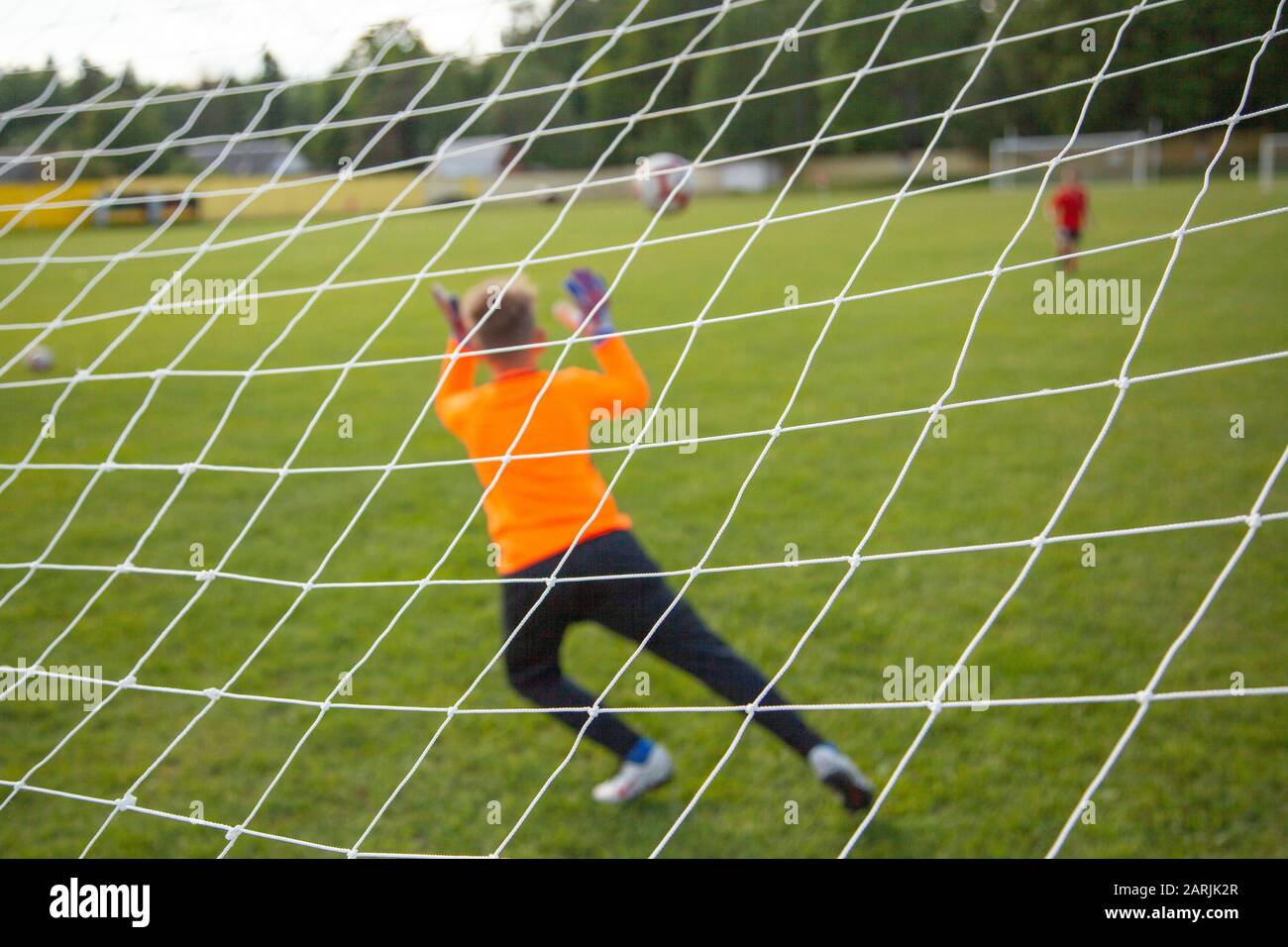 Goalkeeper catches the ball. Goal net in focus. Sports competition ...