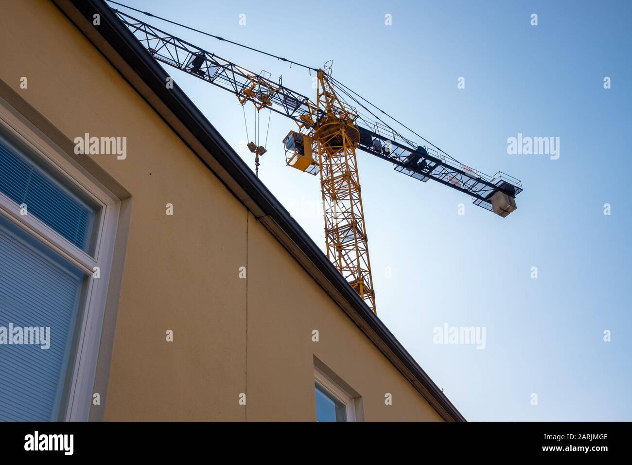 Yellow tower crane behind high-rise building Stock Photo - Alamy