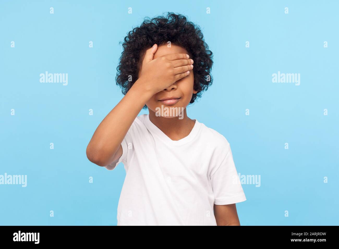 I'm not watching. Portrait of cute little boy with curls covering eyes ...