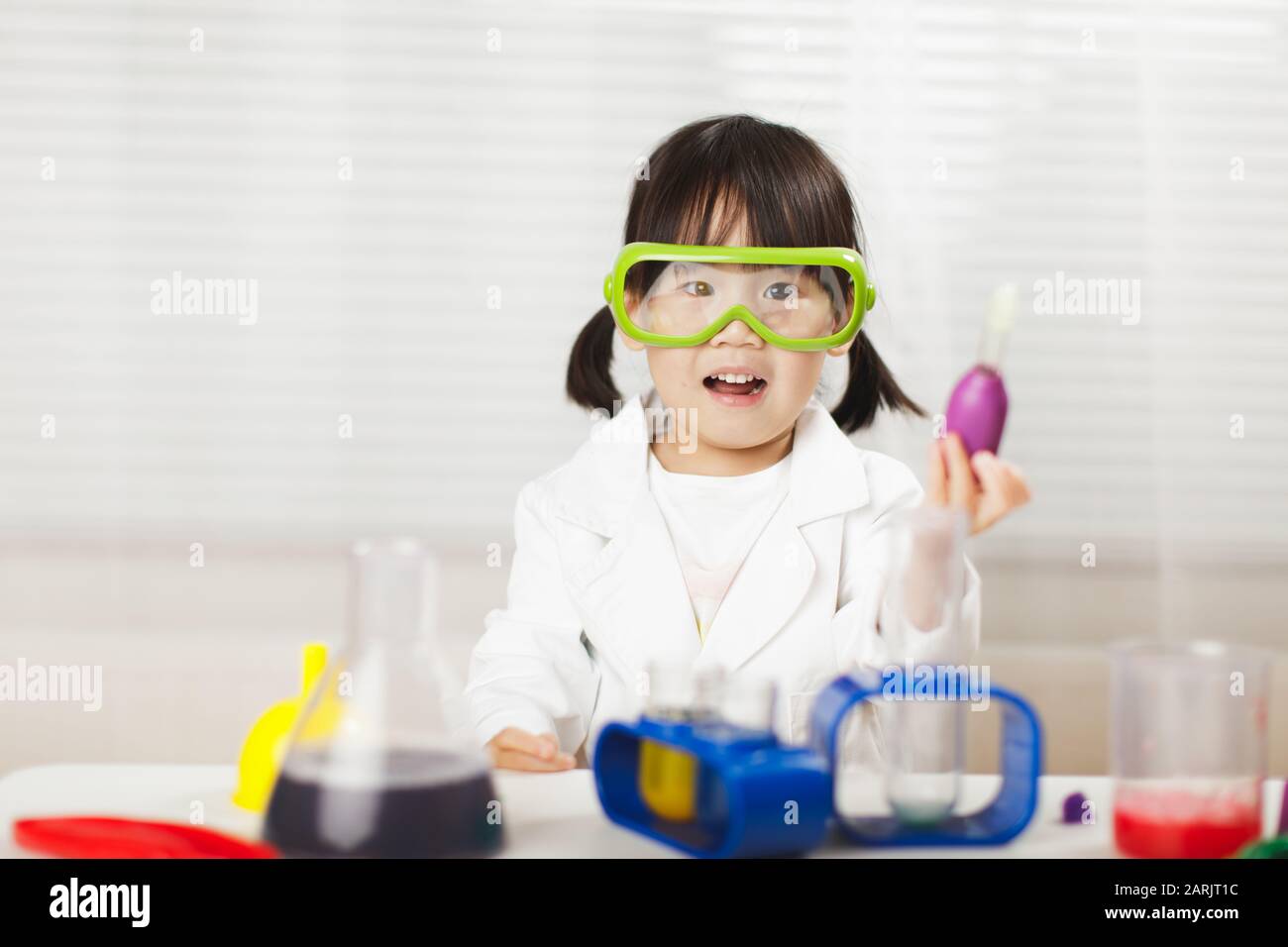 toddler girl pretend play scientist role at home against white ...