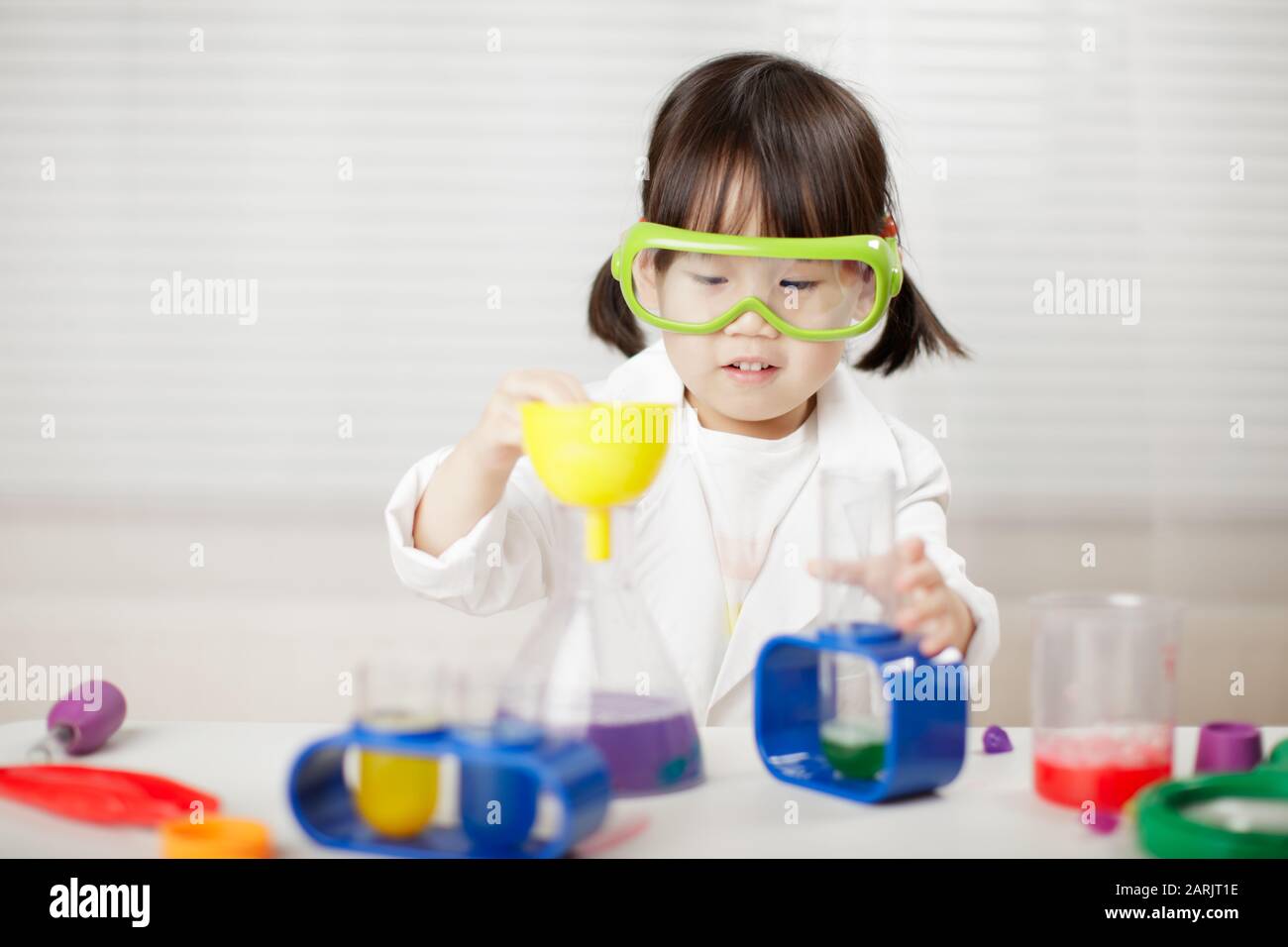 toddler girl pretend play scientist role at home against white ...