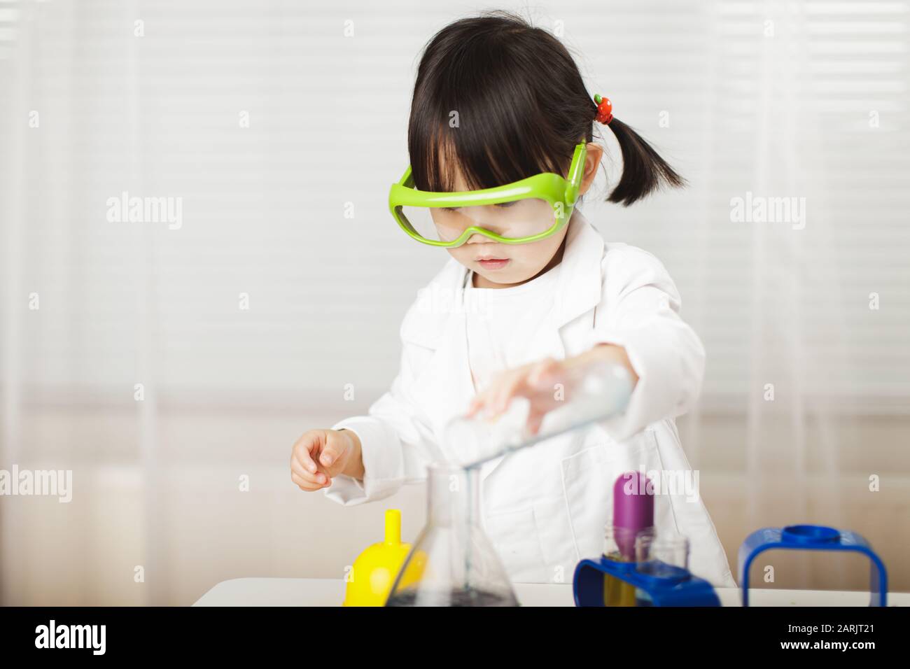 toddler girl pretend play scientist role at home against white ...