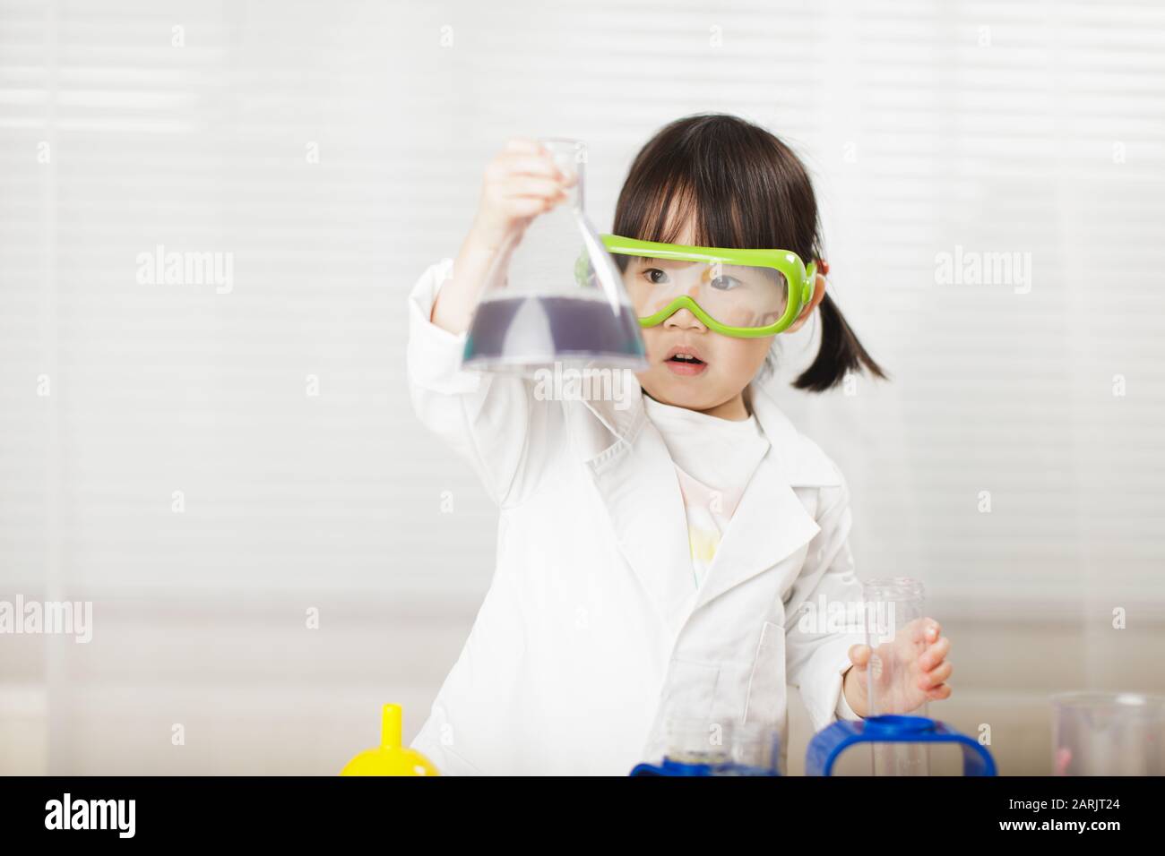 toddler girl pretend play scientist role at home against white ...