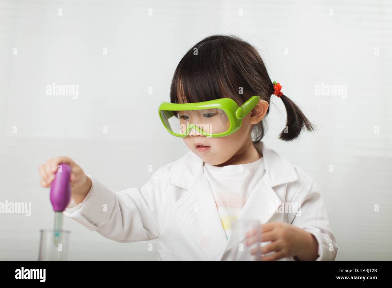 toddler girl pretend play scientist role at home against white ...