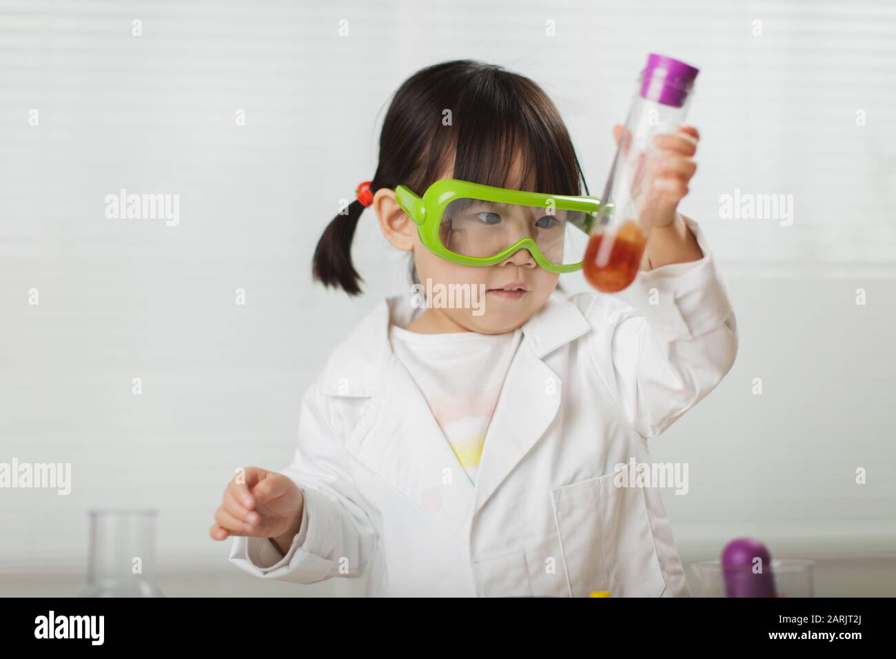 toddler girl pretend play scientist role at home against white ...