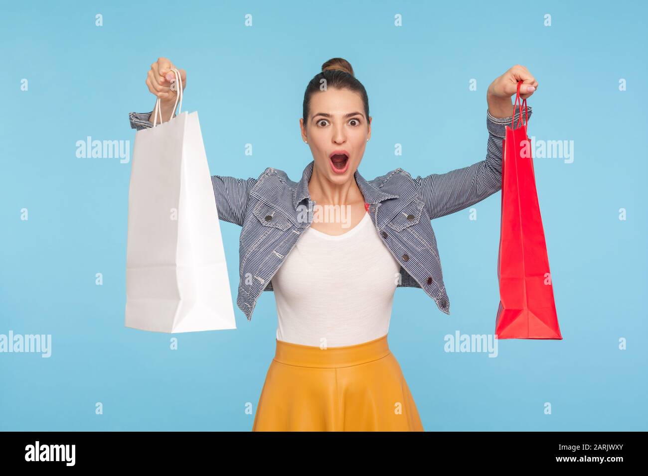 Amazed shopaholic. Young fashionably dressed woman with hair bun ...
