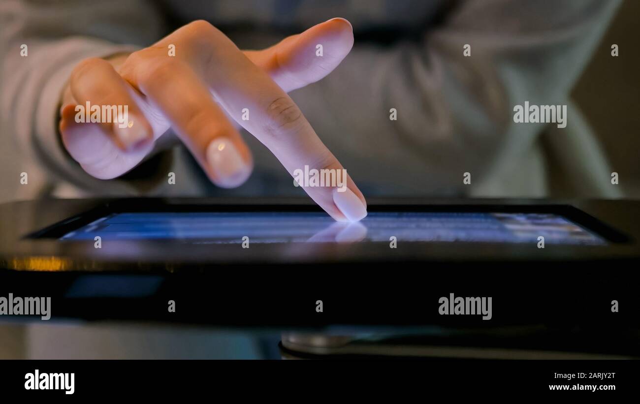 Woman hand using touchscreen display of floor standing black tablet ...