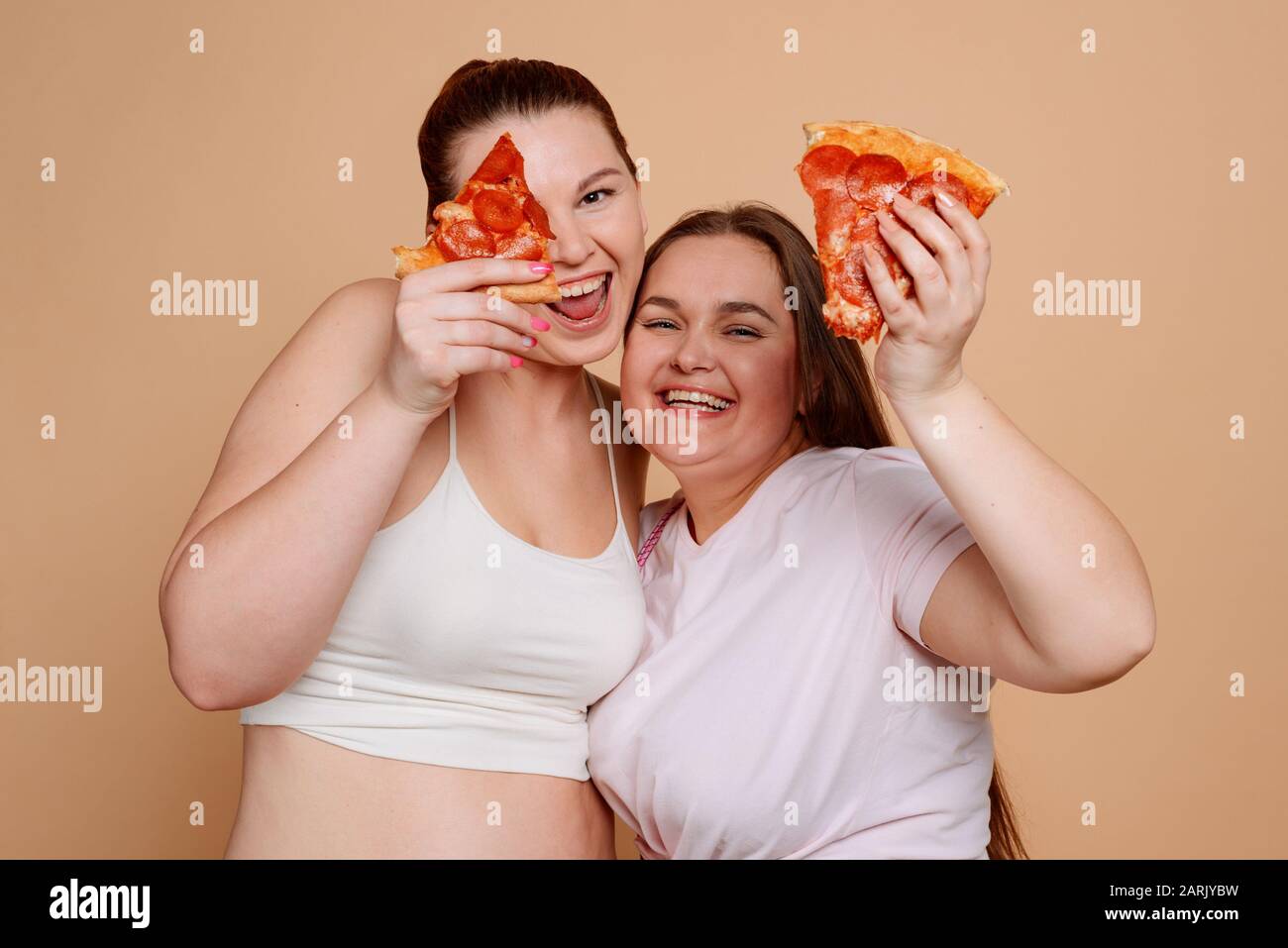 Two fat friends eating pizza and laughing on beige background Stock ...