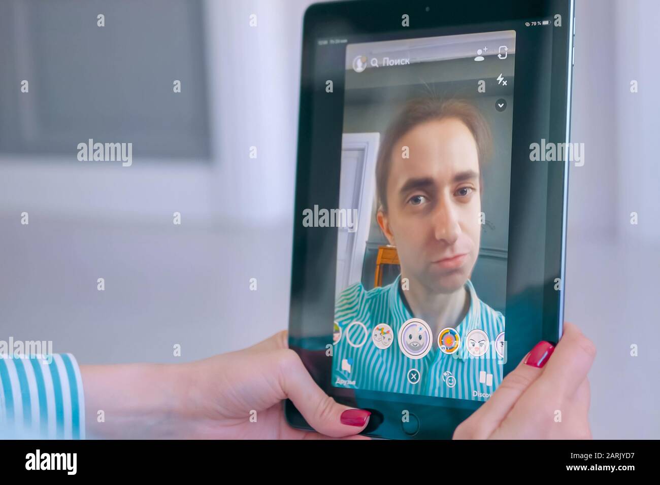 Woman using Snapchat multimedia messaging app with face mask on tablet ...