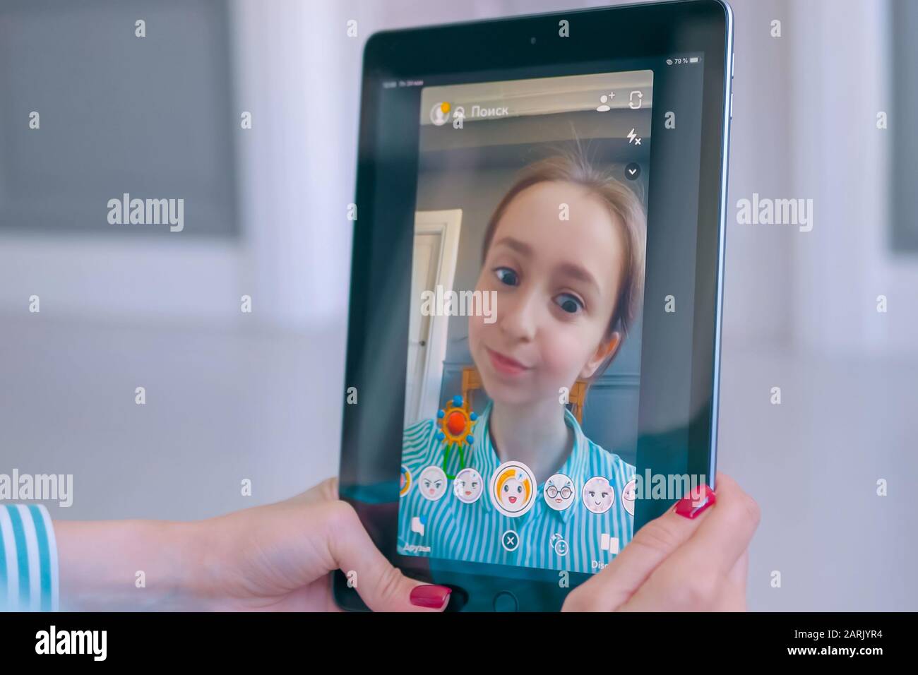Woman using Snapchat multimedia messaging app with face mask on tablet ...
