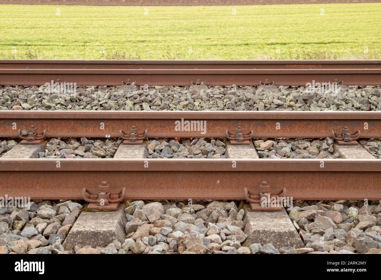 tracks with concrete sleepers, rust on the side Stock Photo - Alamy