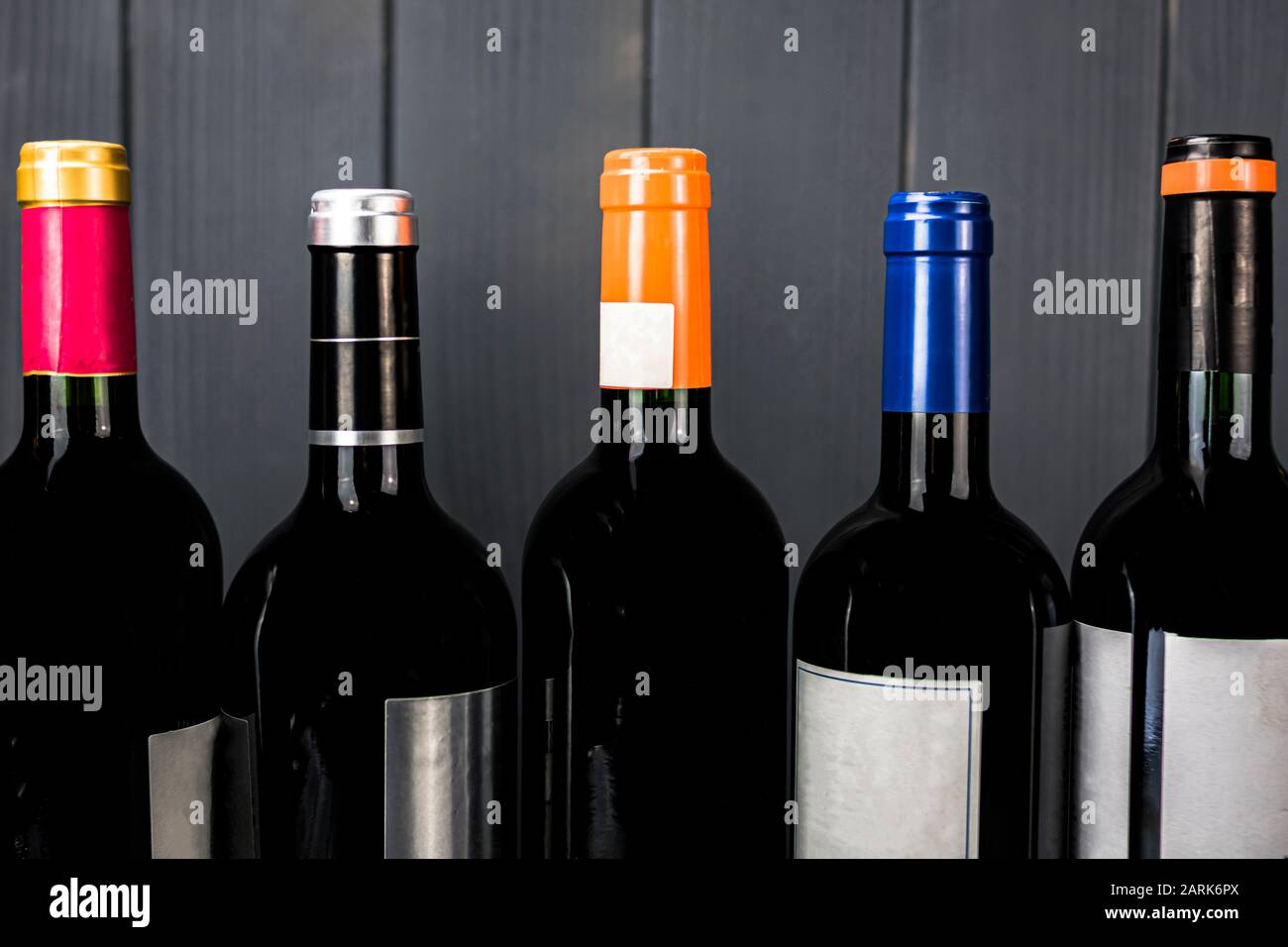 Bottles of red wine from different manufacturers in well-lit gray ...