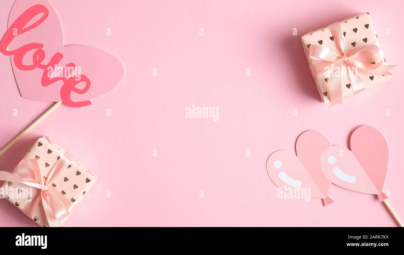 Valentines Day frame border of gifts, heart shaped party props on pink ...
