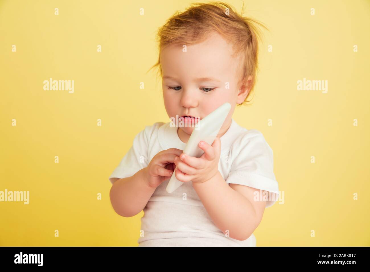 Calling mom. Caucasian little girl, children isolated on yellow studio ...