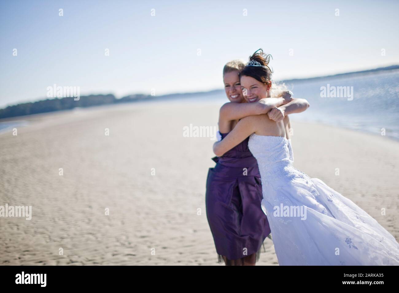 Bride and bridesmaid hugging on the beach Stock Photo - Alamy