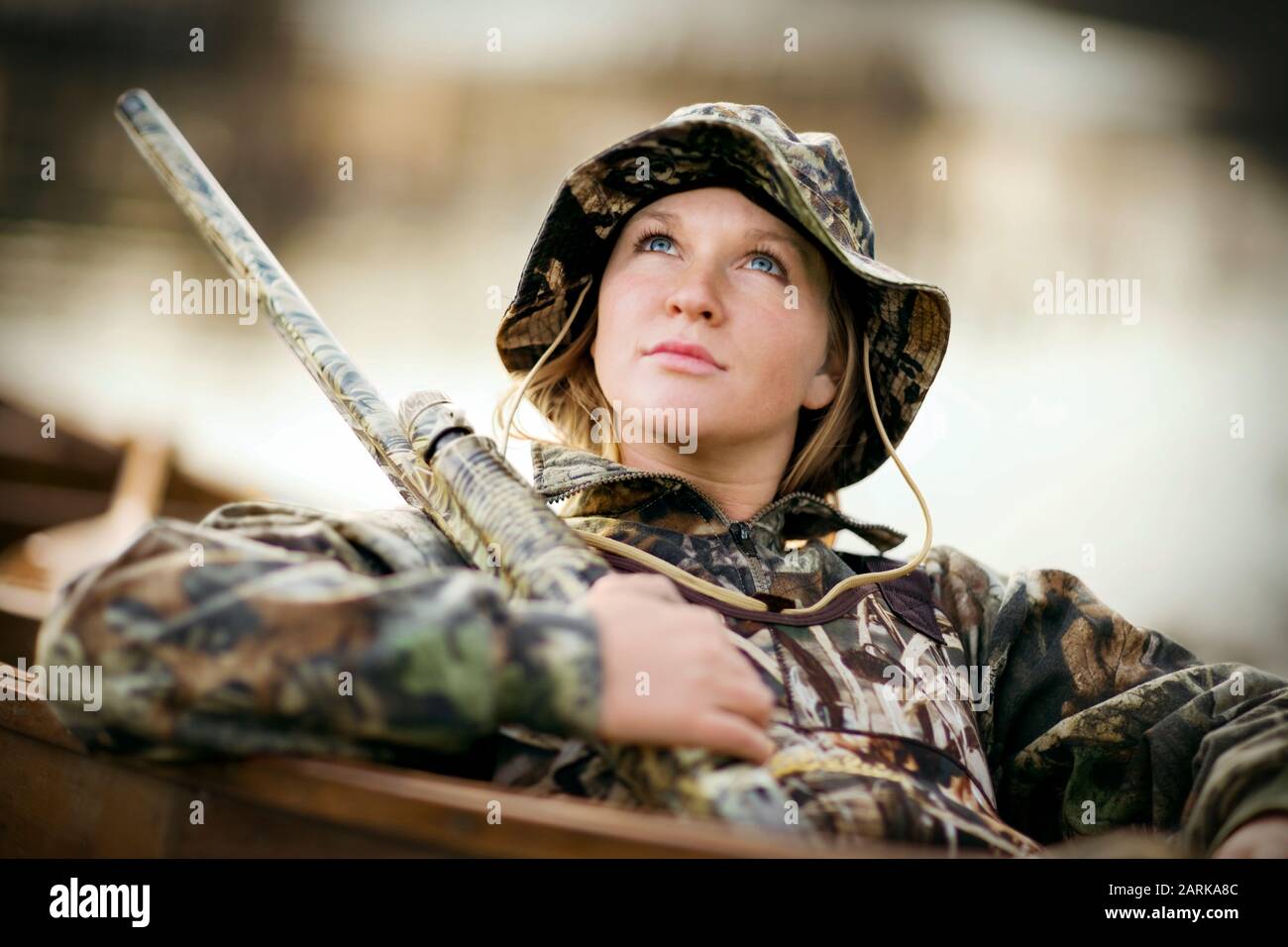 Young woman sitting in a boat holding a rifle Stock Photo - Alamy