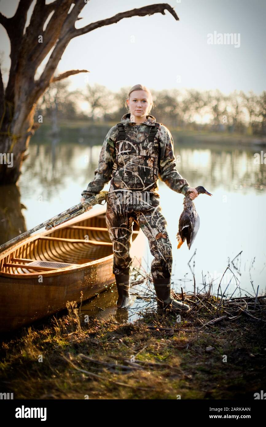 Portrait of a young adult woman duck shooting by a lake Stock Photo - Alamy