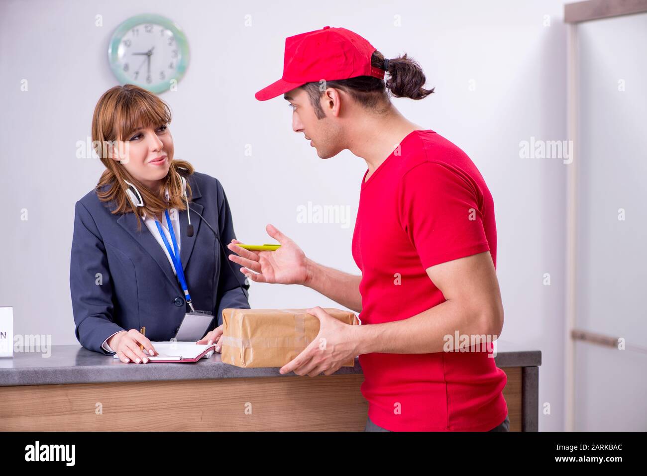 The young male courier delivering box to hotel's reception Stock Photo ...