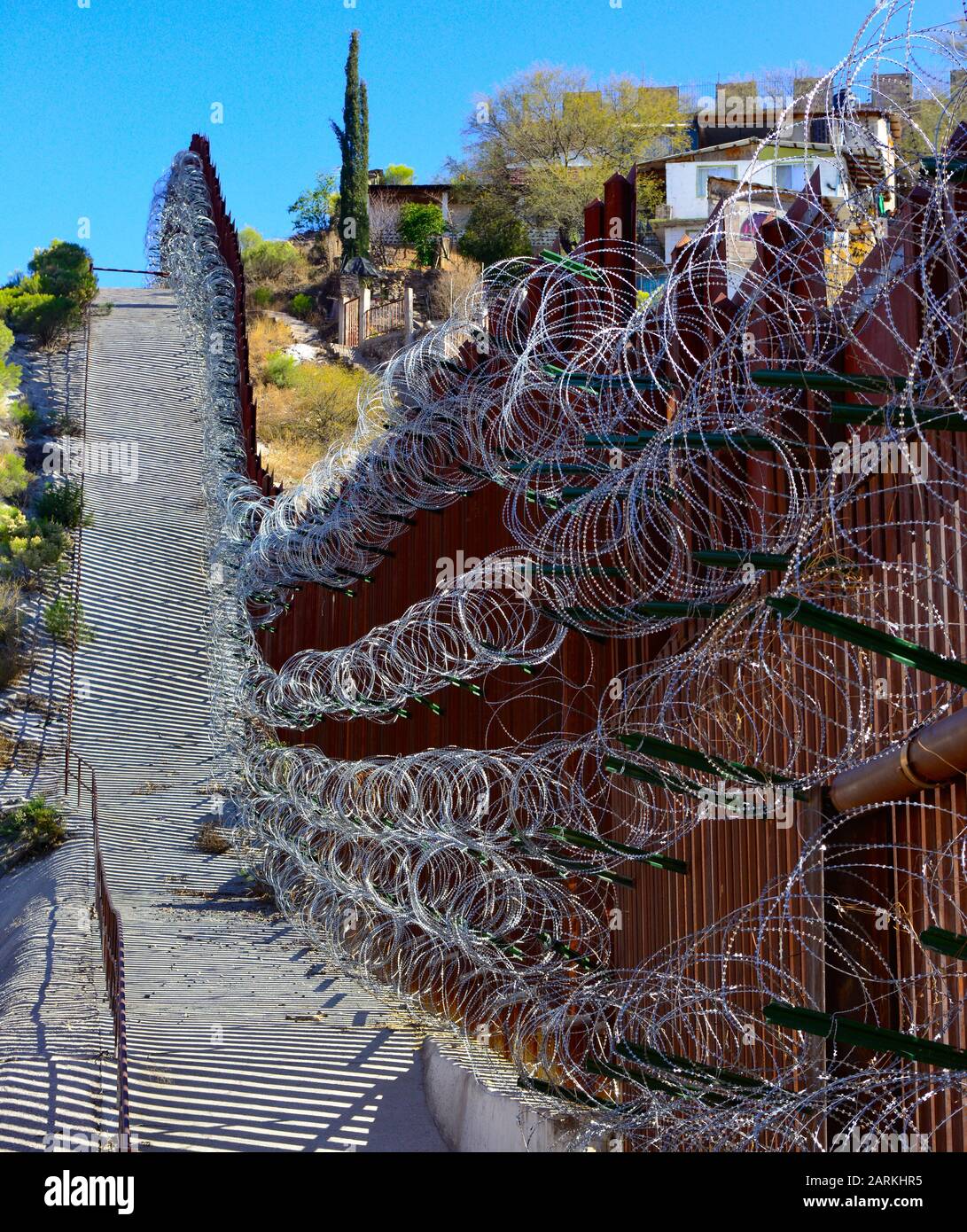 View of US/Mexico international border fence with razor wire following ...
