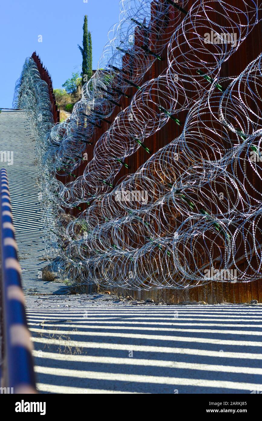 View of US/Mexico metal international border fence with razor wire ...