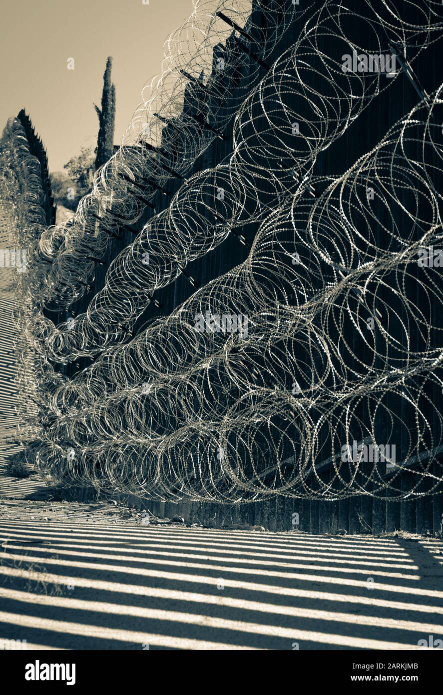 View of US/Mexico international border fence with razor wire following ...