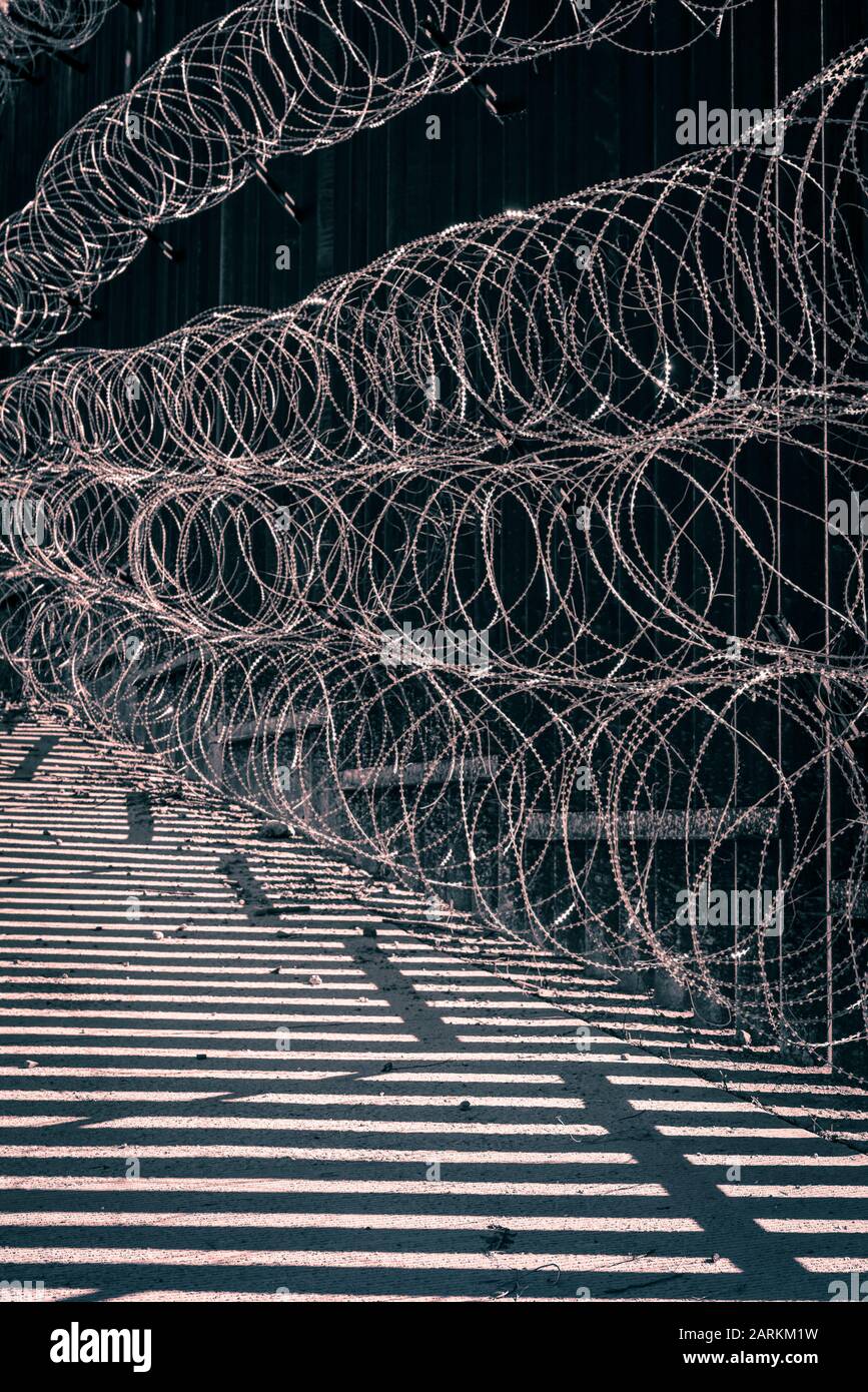 Abstract view of US/Mexico international border fence with razor wire ...