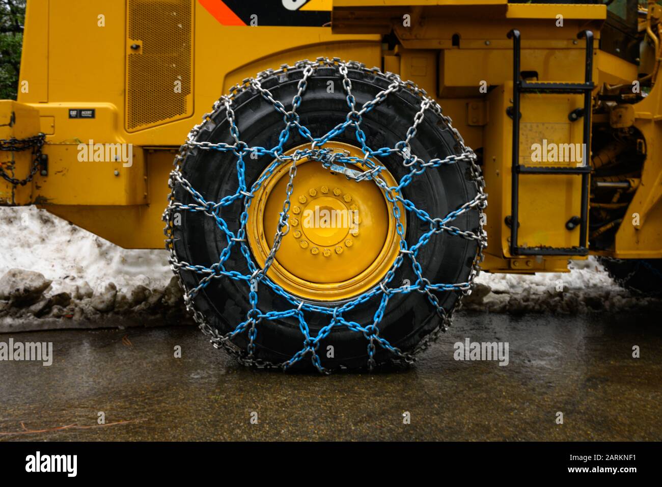 Snow Chains on Large Tire parked along side wet road Stock Photo - Alamy