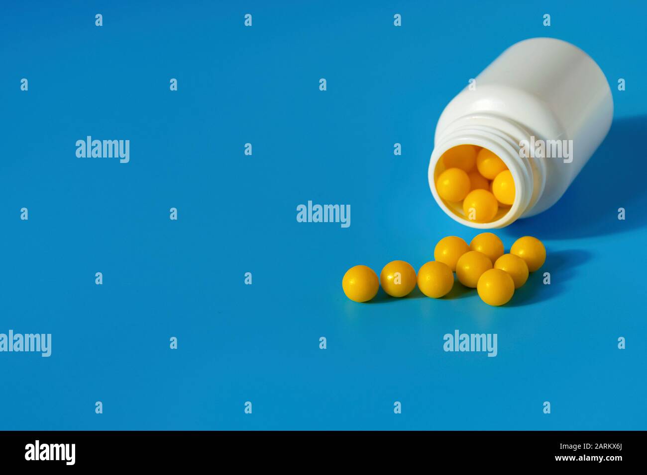 Yellow vitamins pour out from a pill bubble on a blue background ...