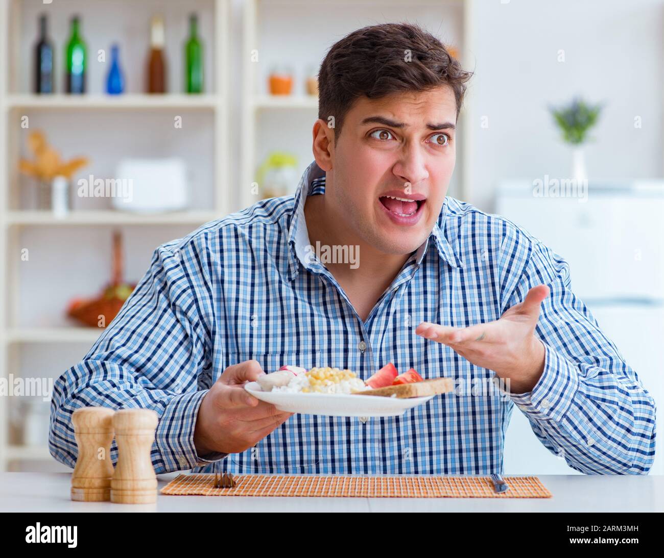 The young husband eating tasteless food at home for lunch Stock Photo ...