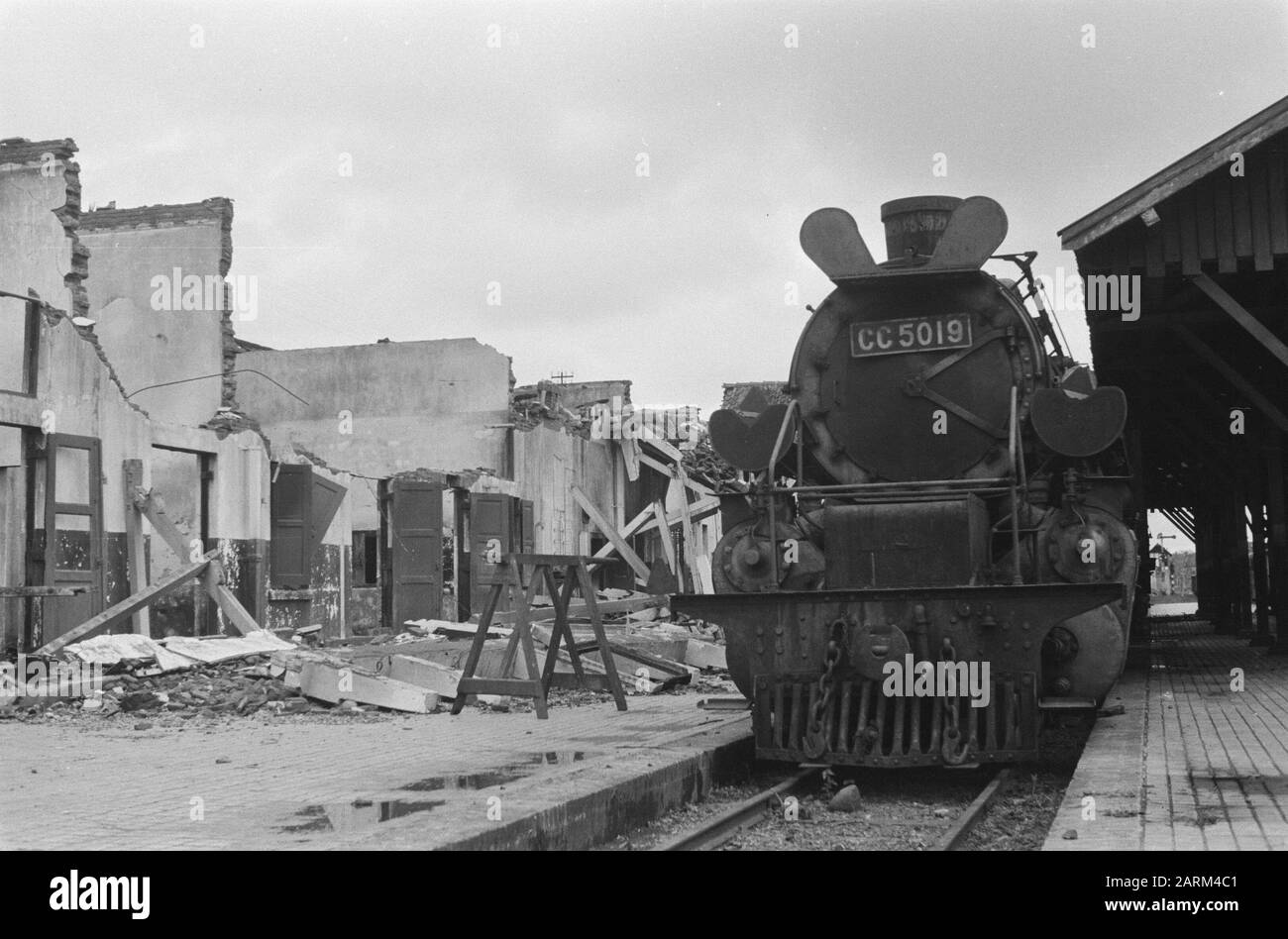 Destroyed station building with a steam locomotive in the foreground ...
