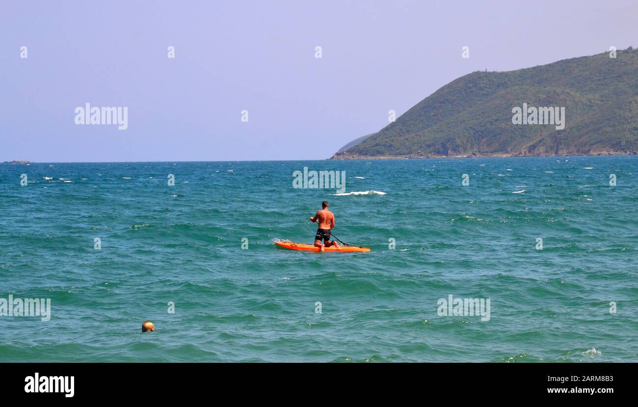 A man paddles a paddle board at sea off the coast at the seaside resort ...