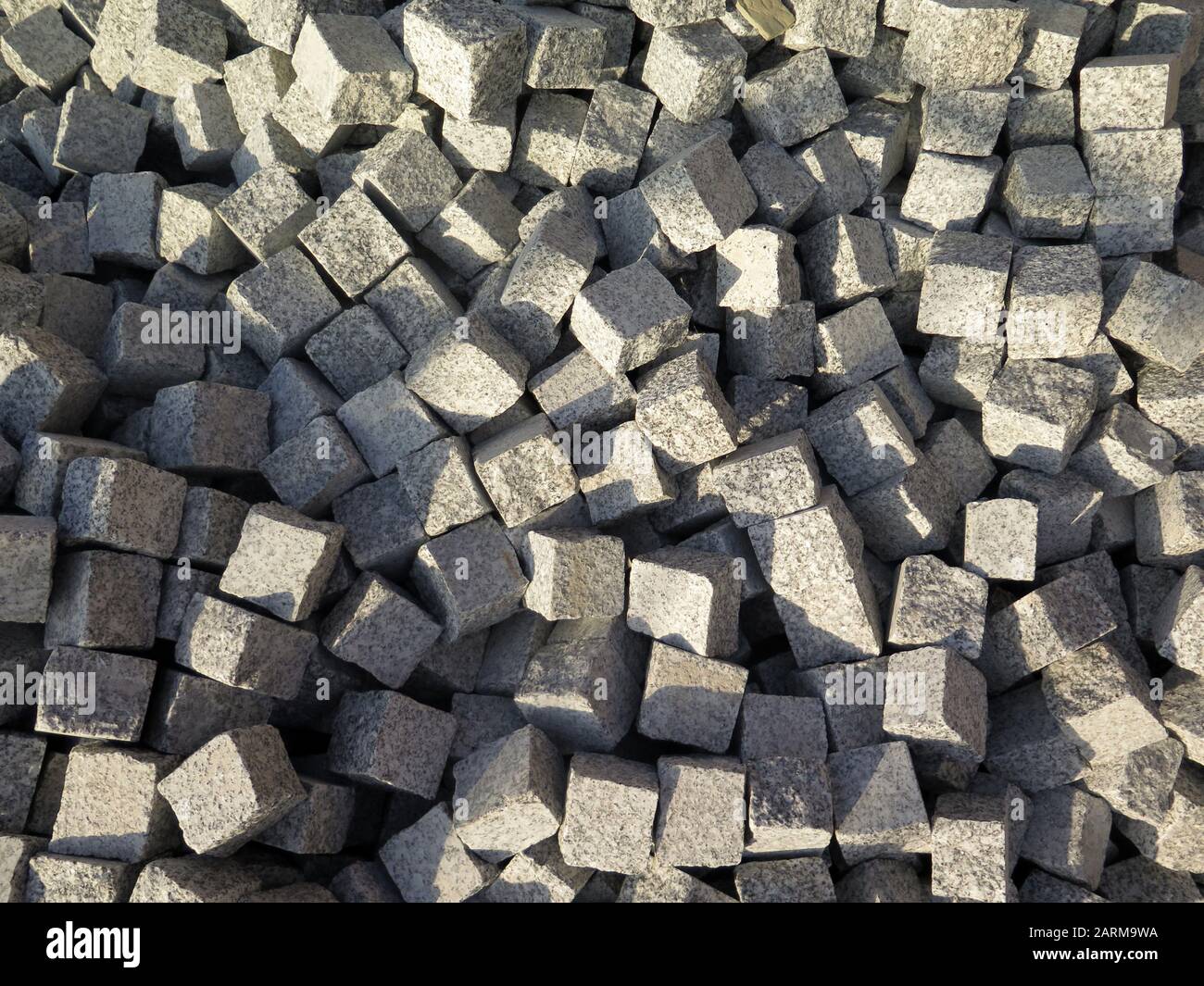 Pile of small cubed granite paving stones ready for laying on village ...