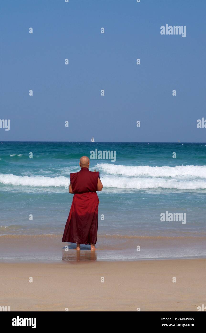 Rear view of a female buddhist monk at the seashore while praying at ...
