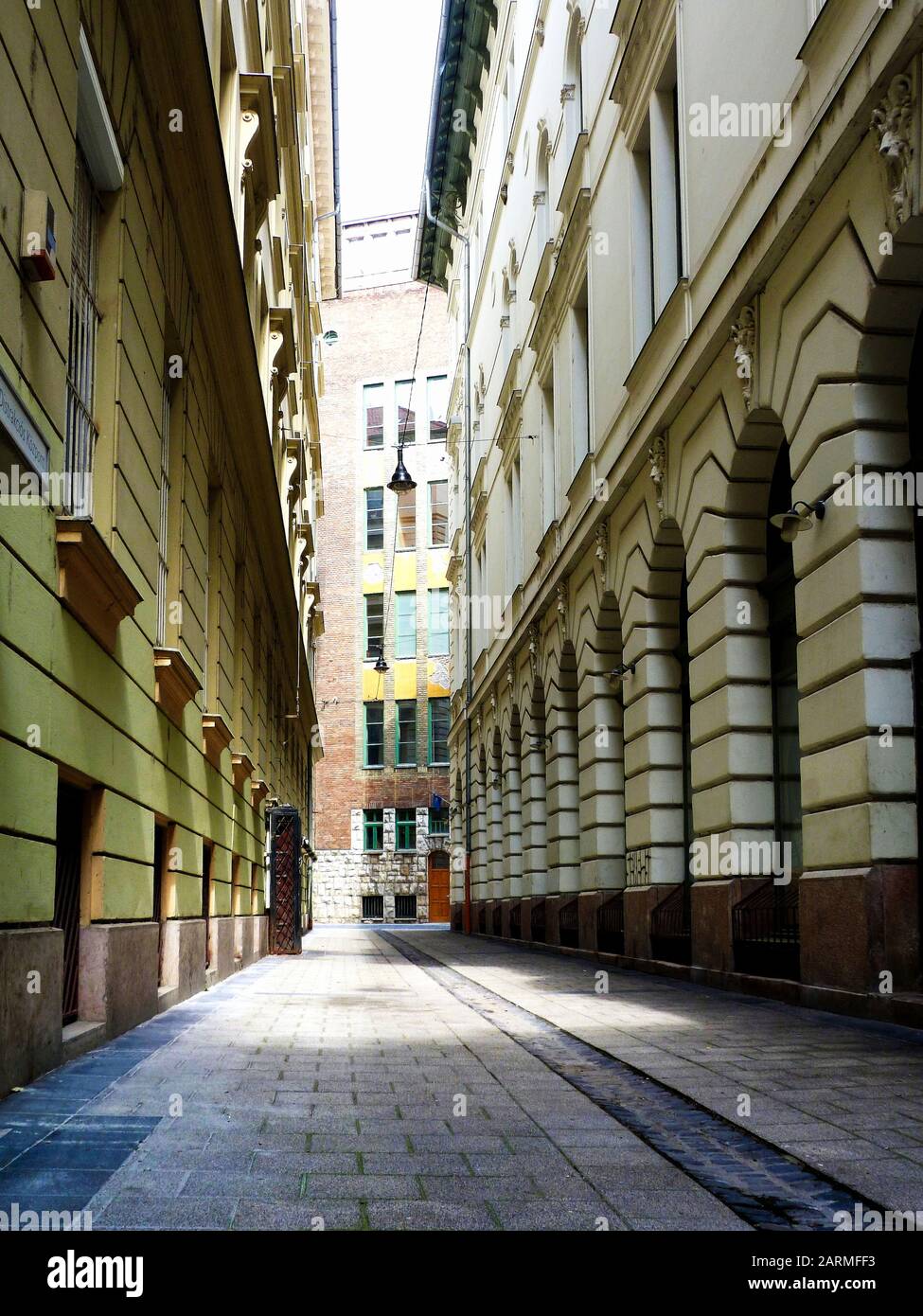 narrow alley. classic buildings and arched arcade. stucco facades with ...