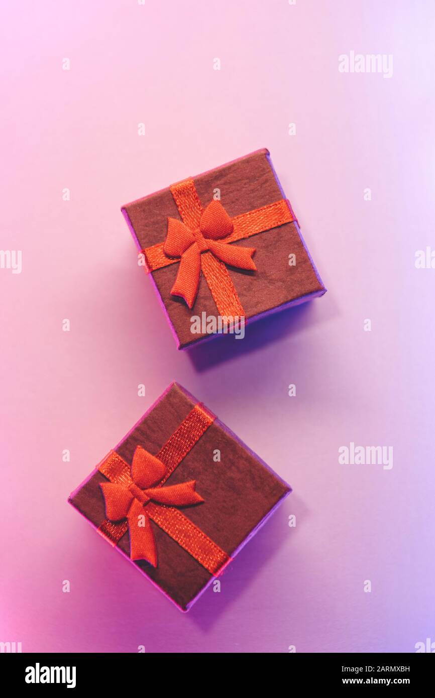 Two red gift boxes on a gradient background lit by neon lights. Holiday ...