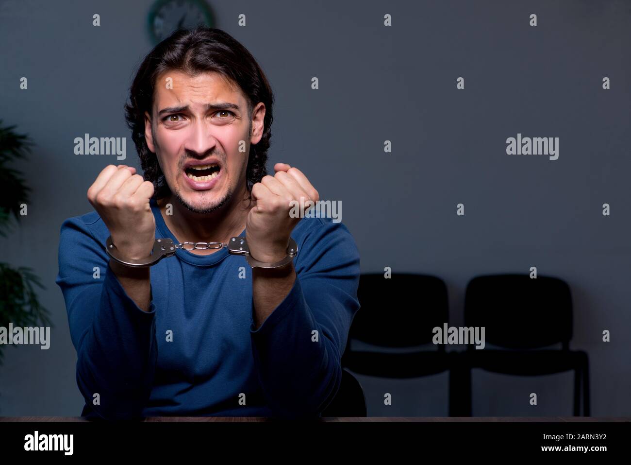 The young convict man sitting in dark room Stock Photo - Alamy