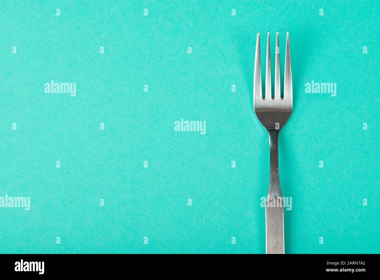 Single fork on a turquoise blue background with space for copy Stock ...
