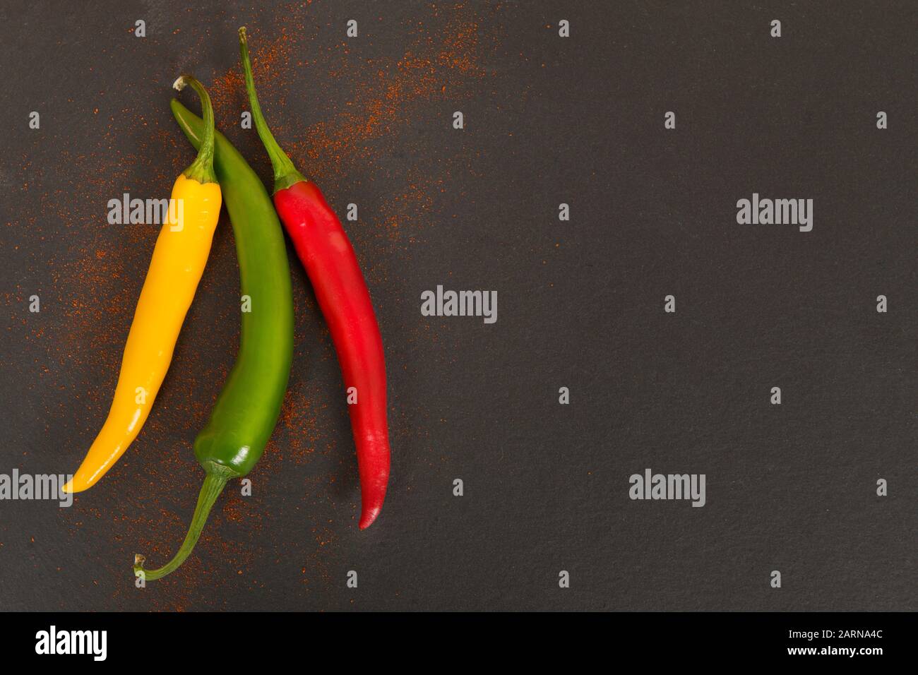 Three colors pepper, a red, yellow and green one and chilli powder on a ...