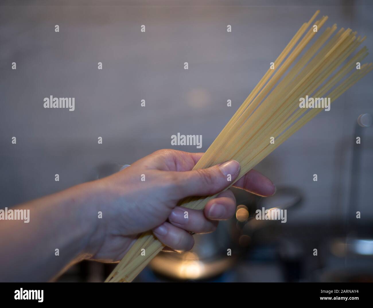 Person holding a bundle of dried Italian spaghetti in a kitchen in ...