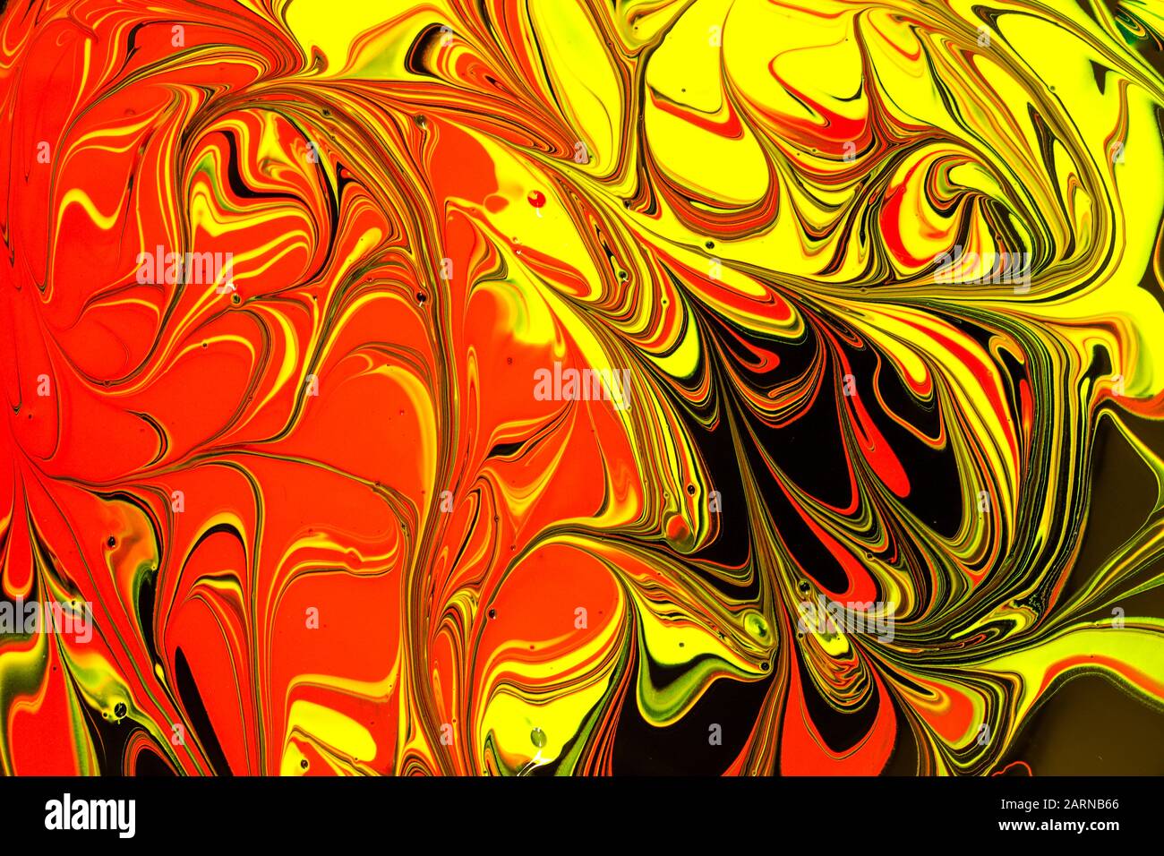 Close up of black, red and yellow liquid paint swirls to make and ...