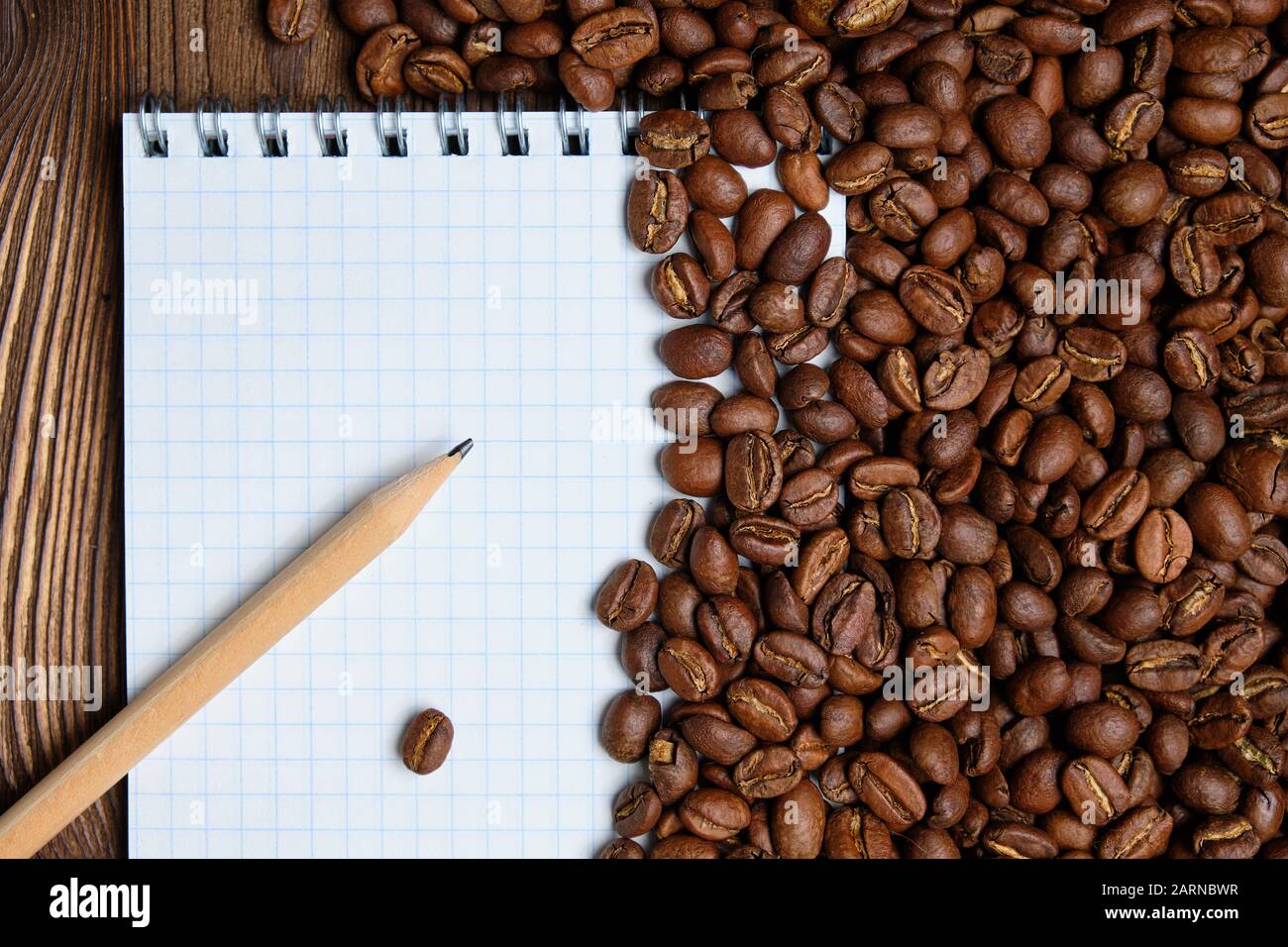 Roasted coffee beans with paper notepad and pencil. Top view. Close up ...