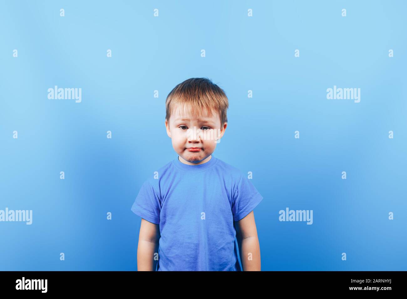 Upset crying sad boy at blue background Stock Photo - Alamy