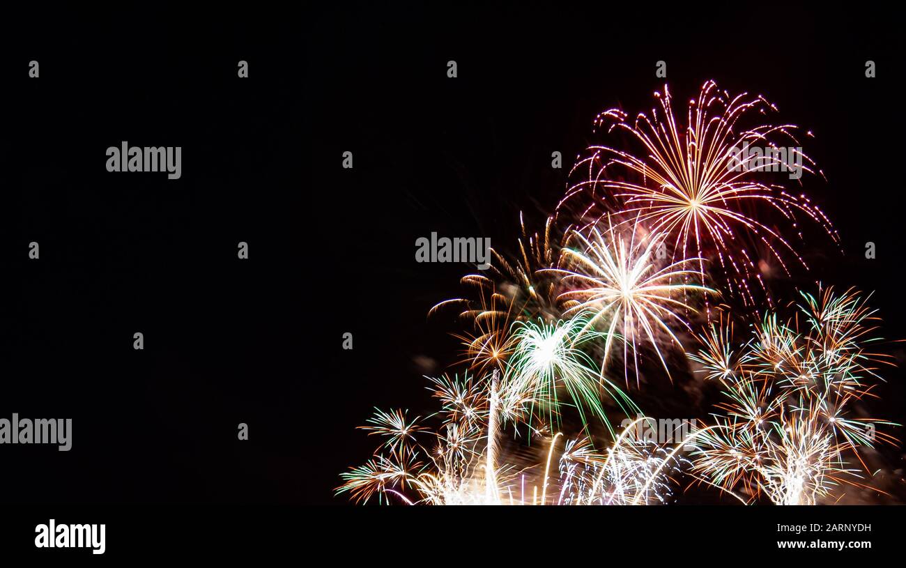 Multiple white starburst fireworks with red, green, and gold highlights ...