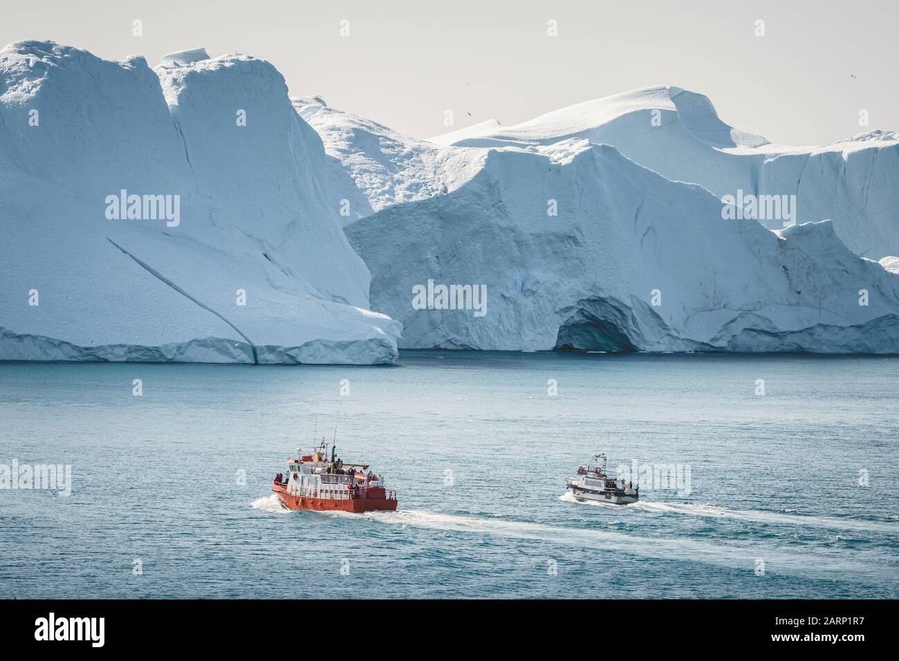 Orange whale Watching tour boat ship with icebergs in background. View ...